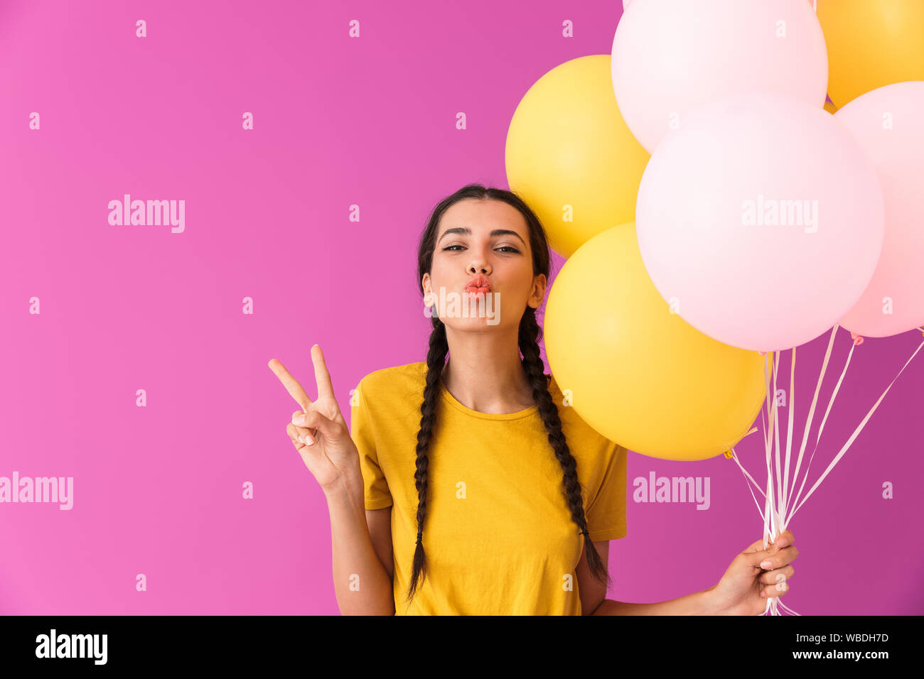 Lovely young brunette girl holding bunch of air balloons and showing ...