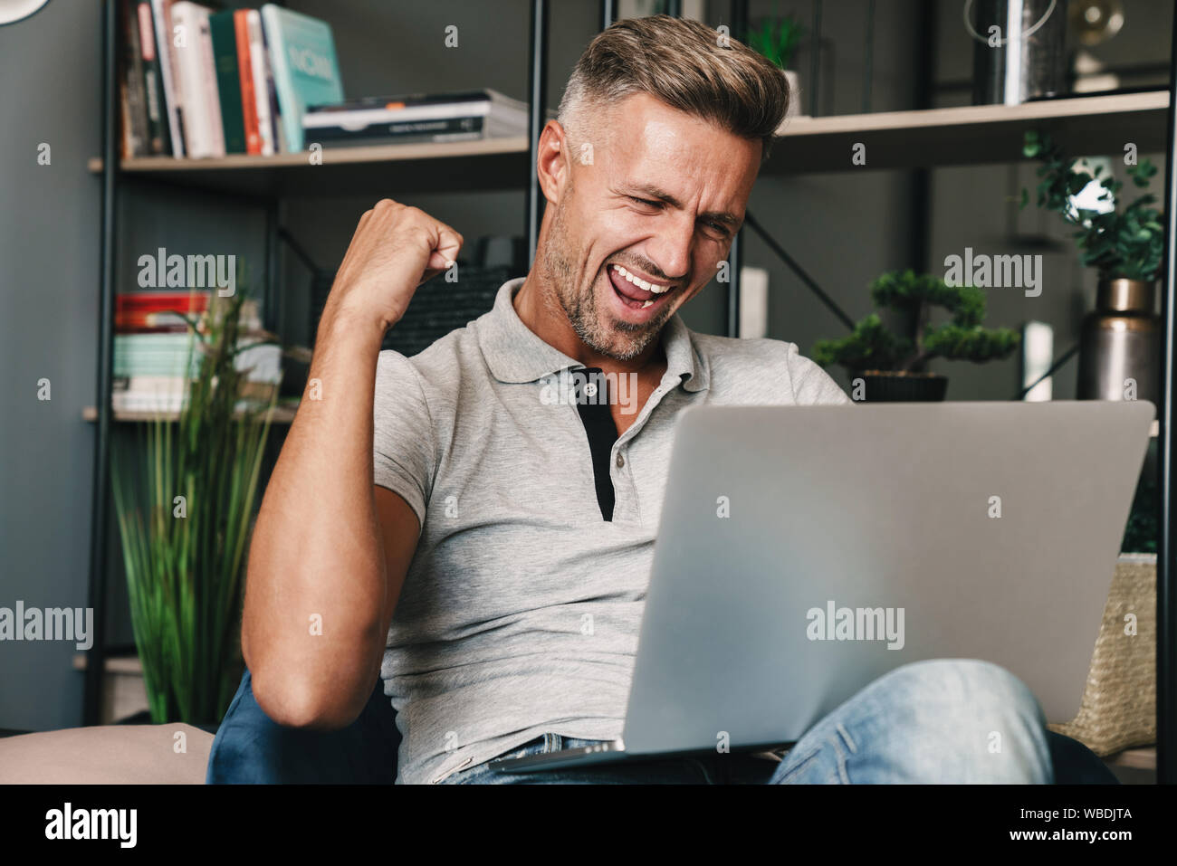 Photo of excited adult man in casual clothing smiling and celebrating ...