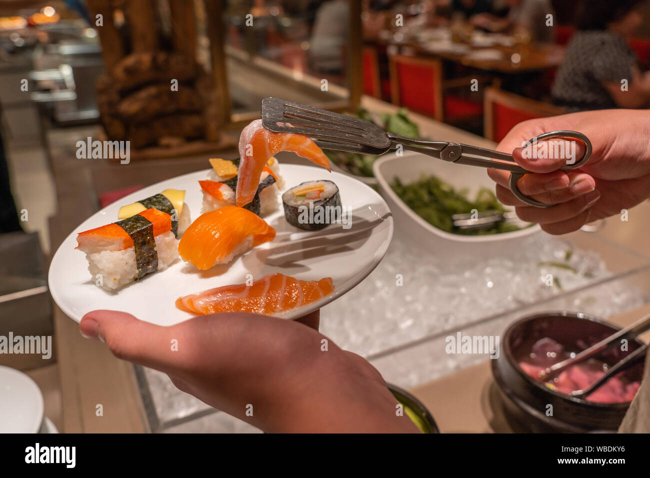 Human picking sashimi into his plate in luxury buffet restaurant Stock ...