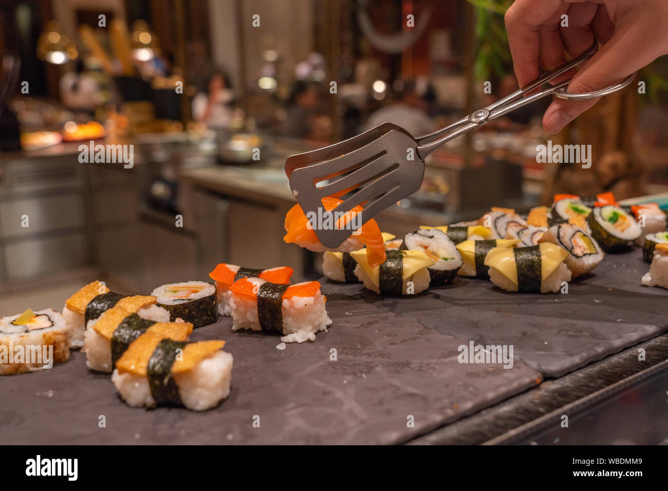 Human hand using tongs picking nigiri sushi in luxury restaurant Stock ...