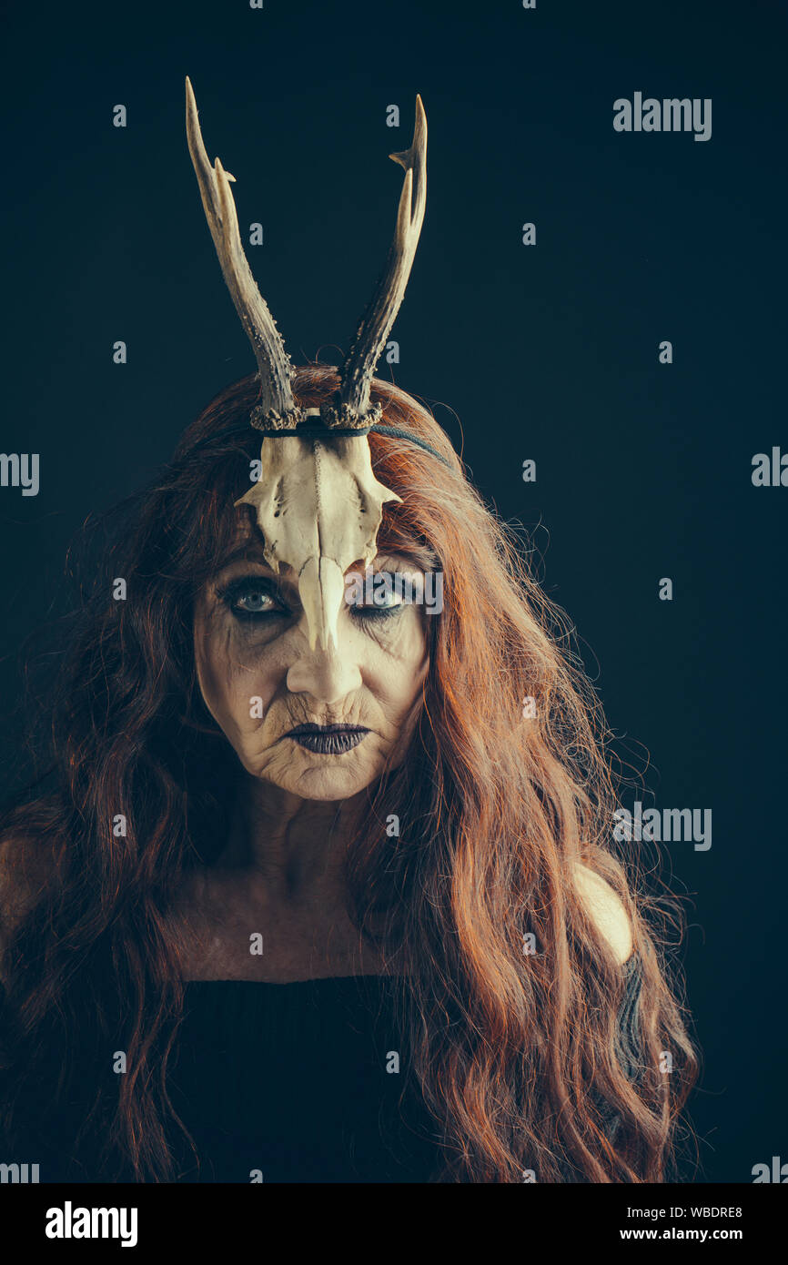 Halloween old lady with candle and antler. Halloween woman in black ...