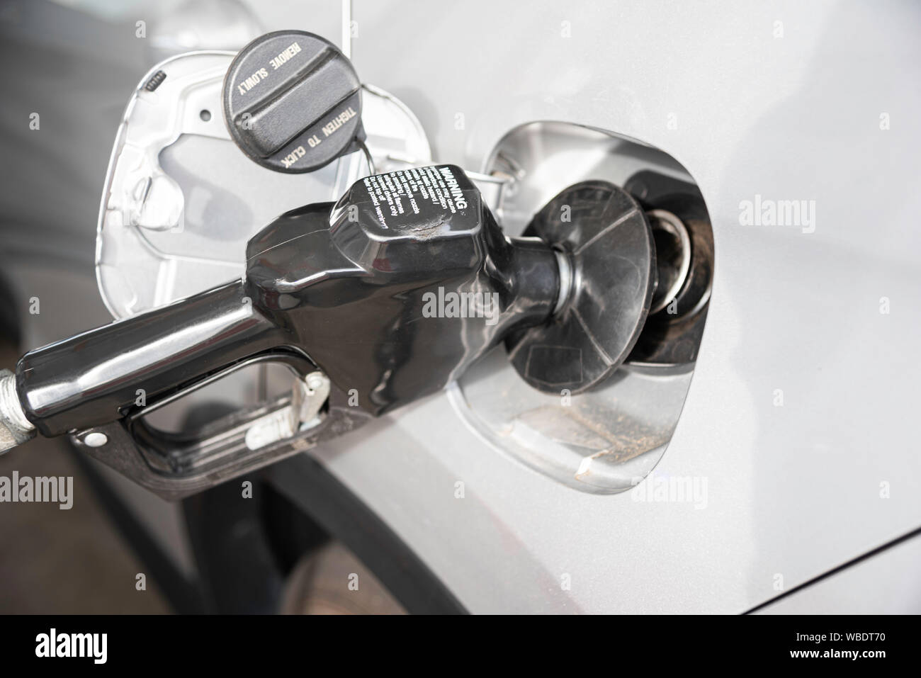 A silver-color vehicle’s empty gas tank is being filled with fuel at ...