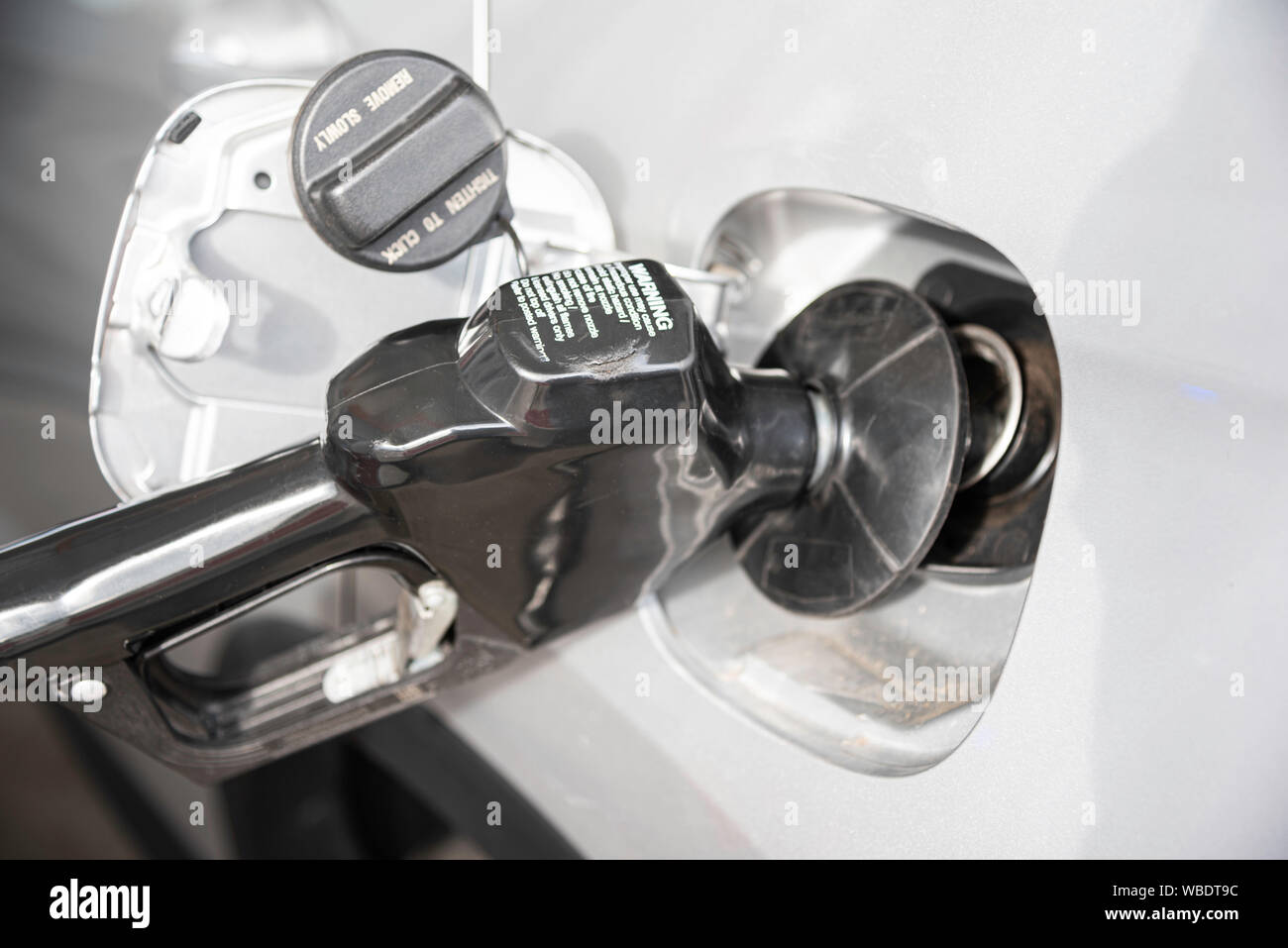 A silver-color vehicle’s empty gas tank is being filled with fuel at ...