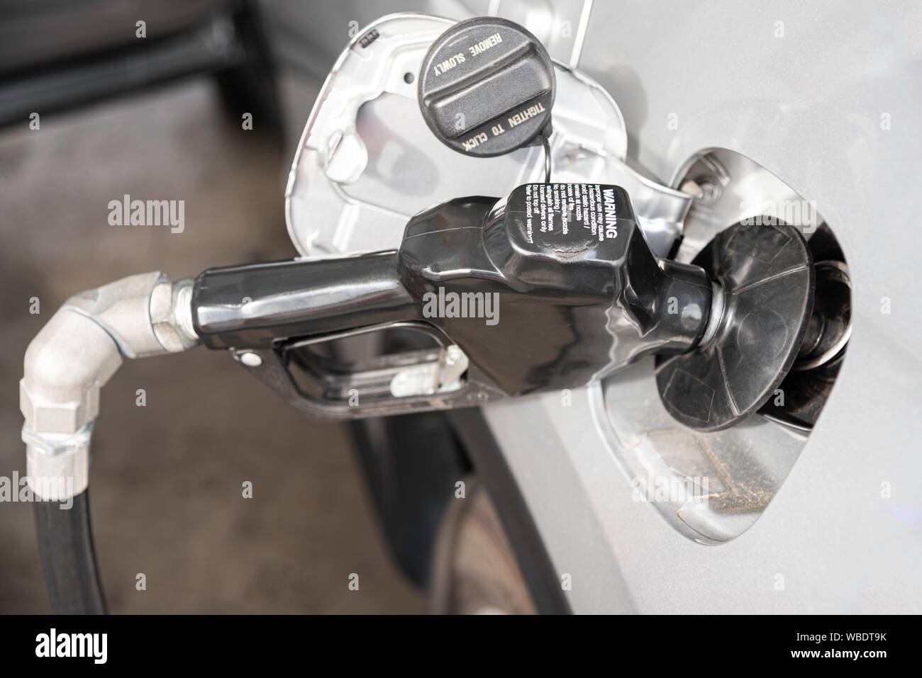 A silver-color vehicle’s empty gas tank is being filled with fuel at ...