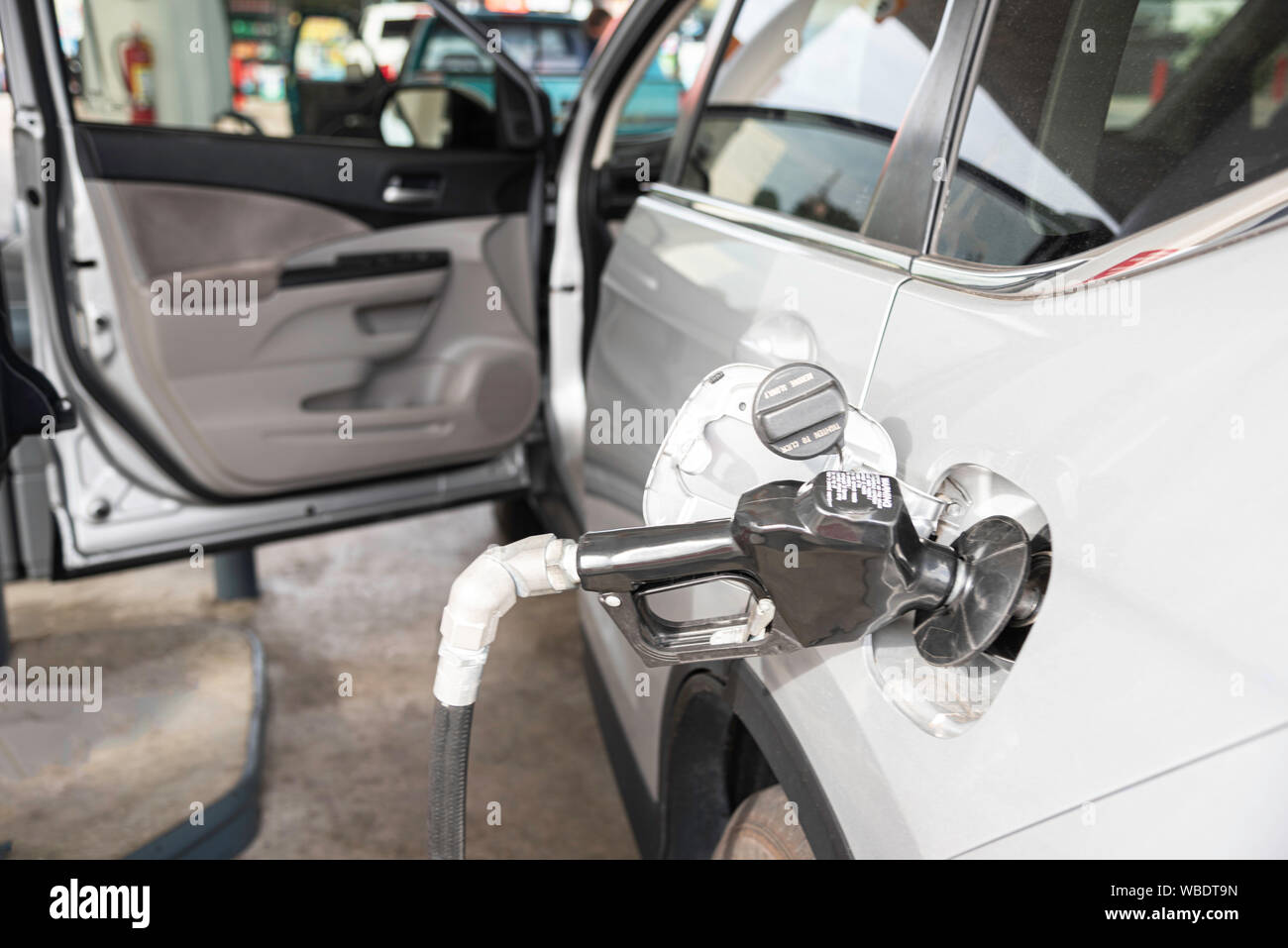 A silver-color vehicle’s empty gas tank is being filled with fuel at ...
