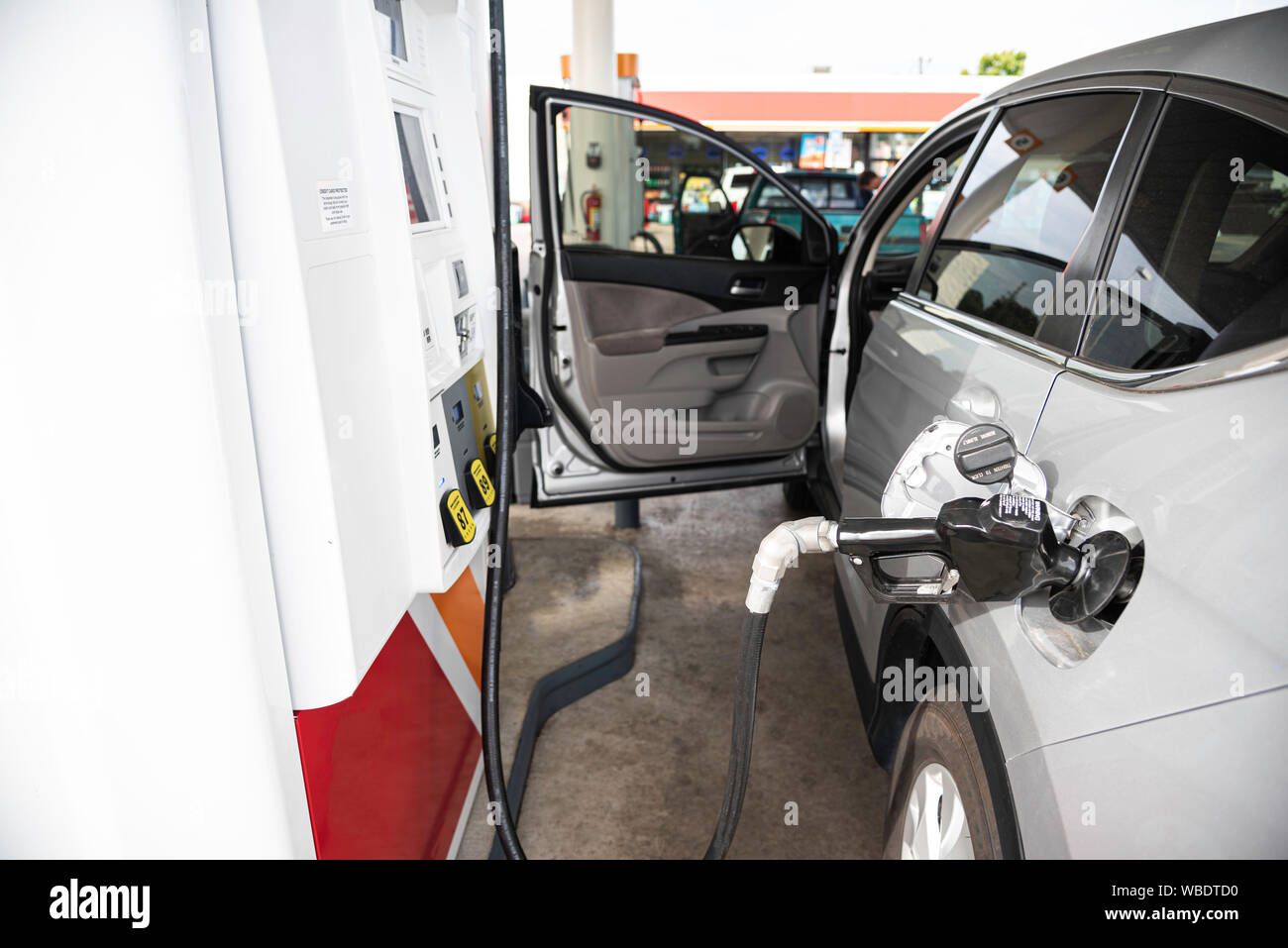 A silver-color vehicle’s empty gas tank is being filled with fuel at ...