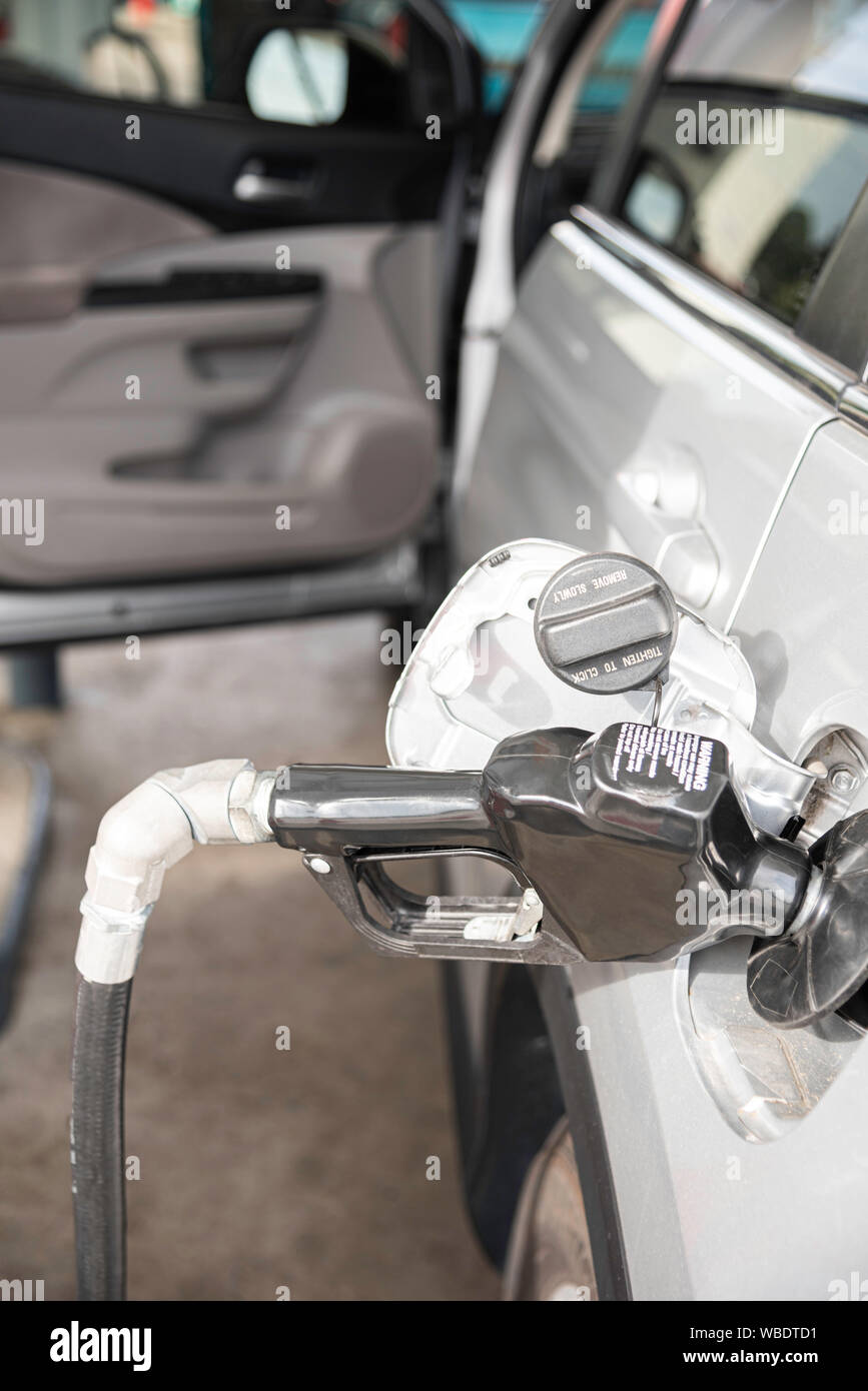 A silver-color vehicle’s empty gas tank is being filled with fuel at ...
