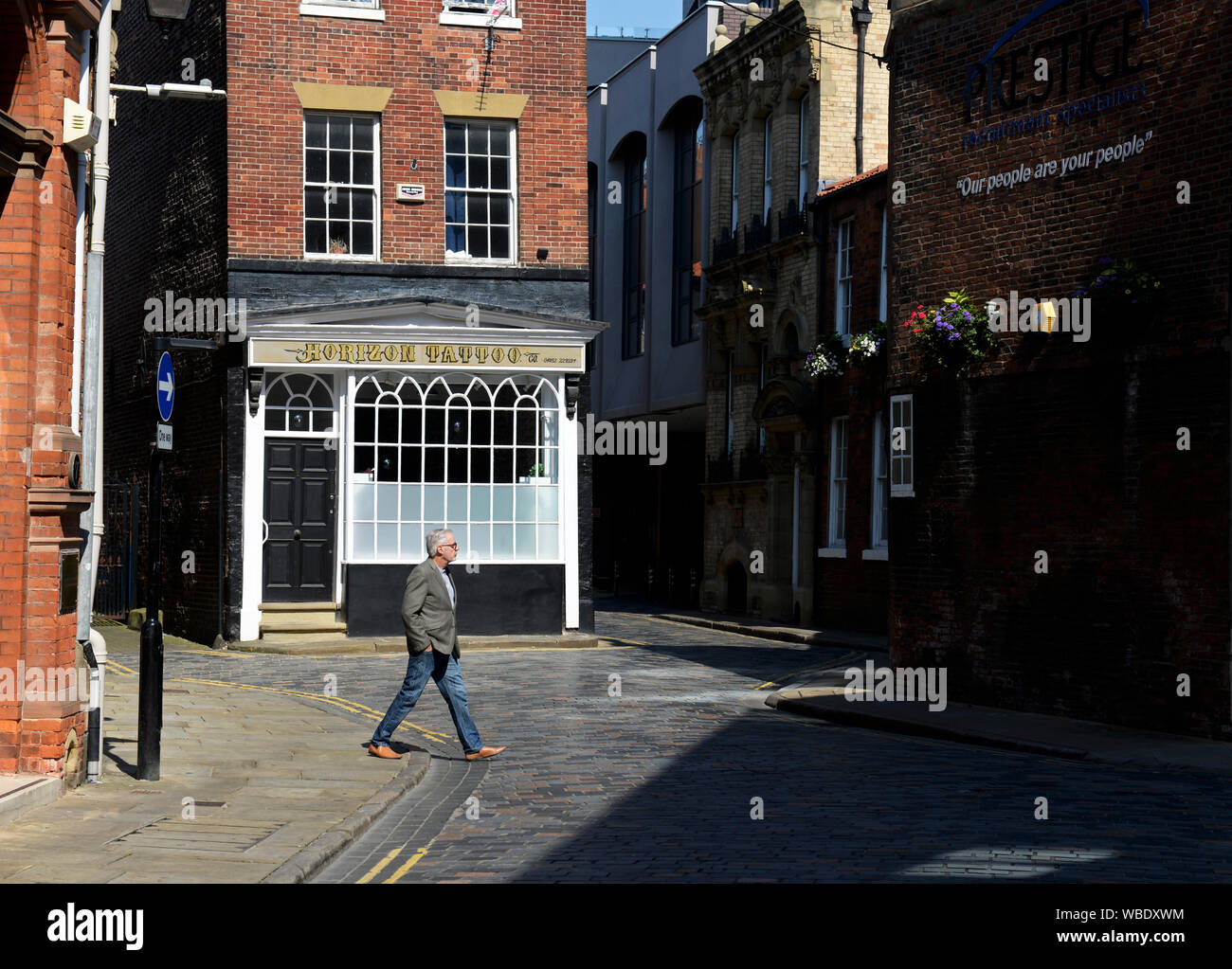 Man crossing cobbled street called The Land of Green Ginger, in the old ...
