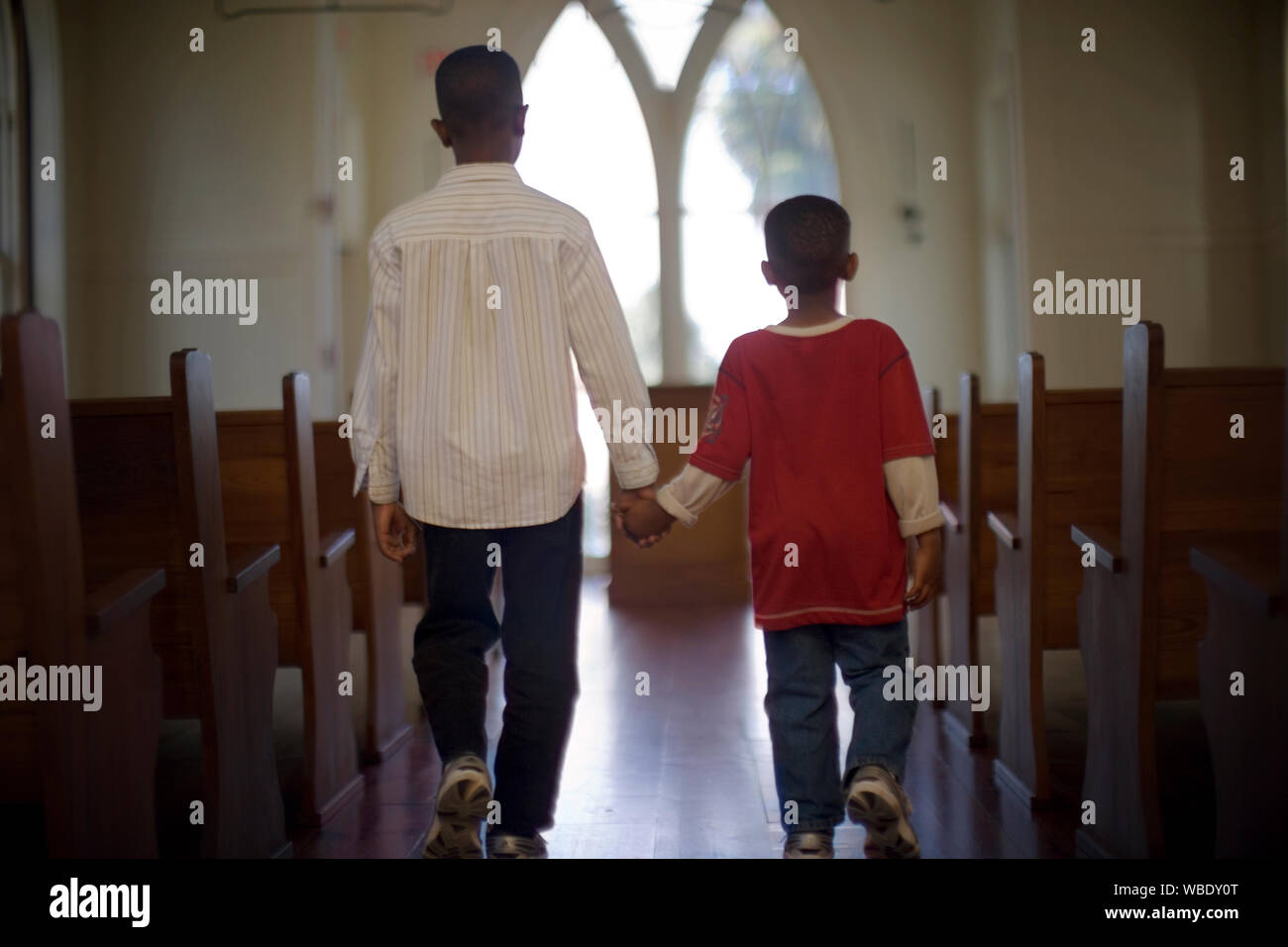 Two boys holding hands while walking down the aisle of a church Stock ...