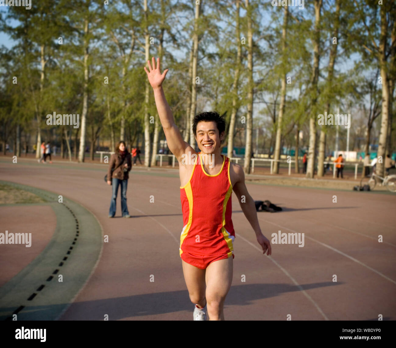 Portrait of a young adult man running around a track and waving Stock ...