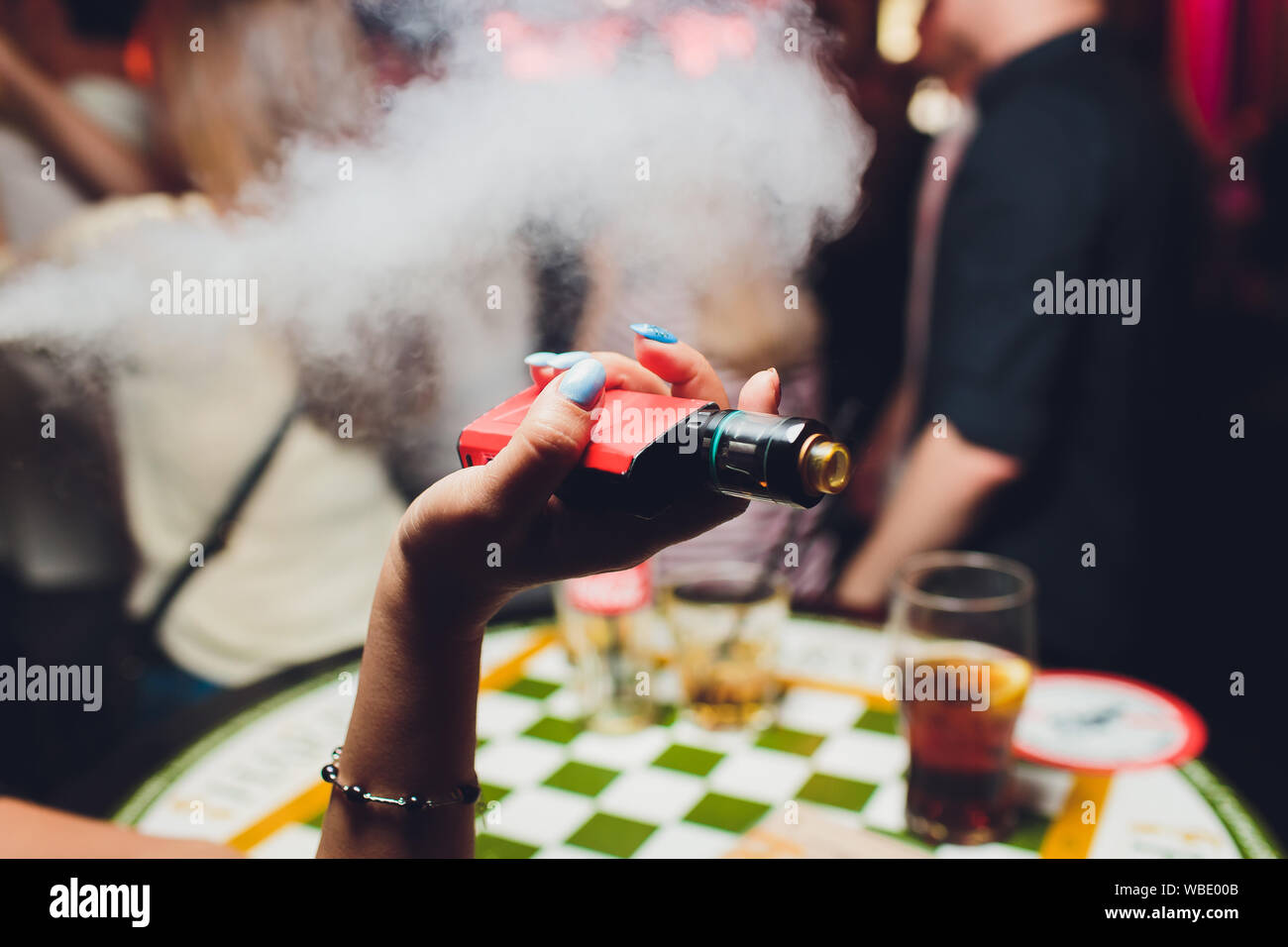 woman smokes a e-cigarette lying on the bed in the room. Smoker's ...