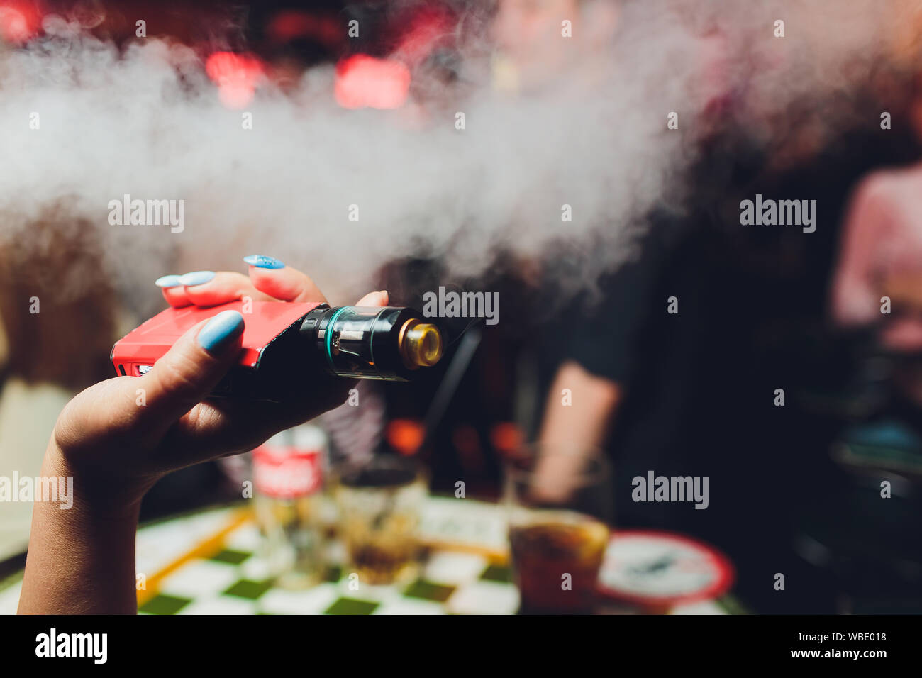 woman smokes a e-cigarette lying on the bed in the room. Smoker's ...
