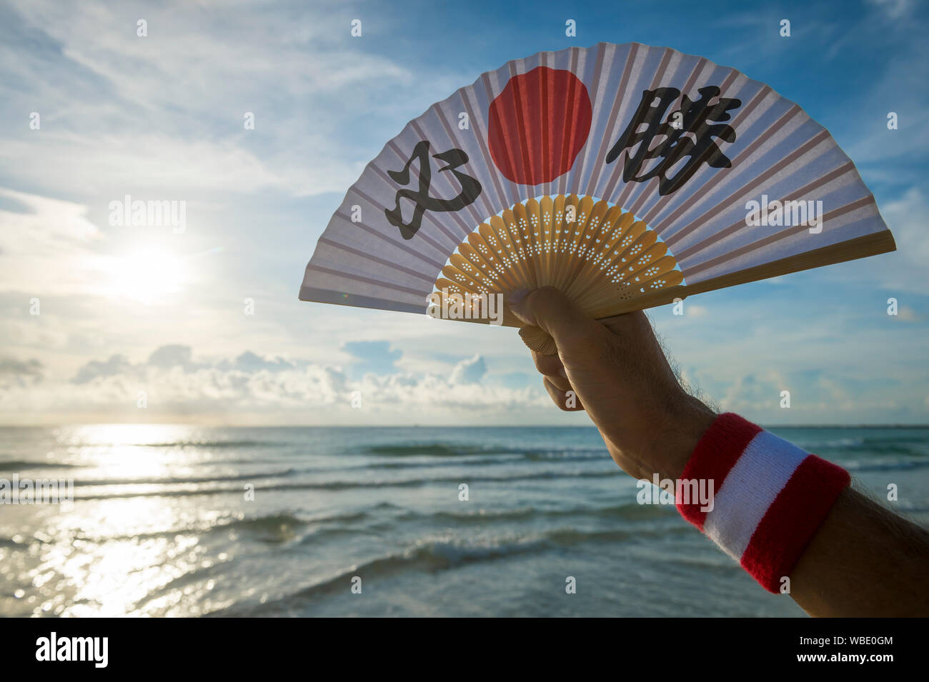 Hand of Japanese sports supporter holding fan decorated with kanji ...