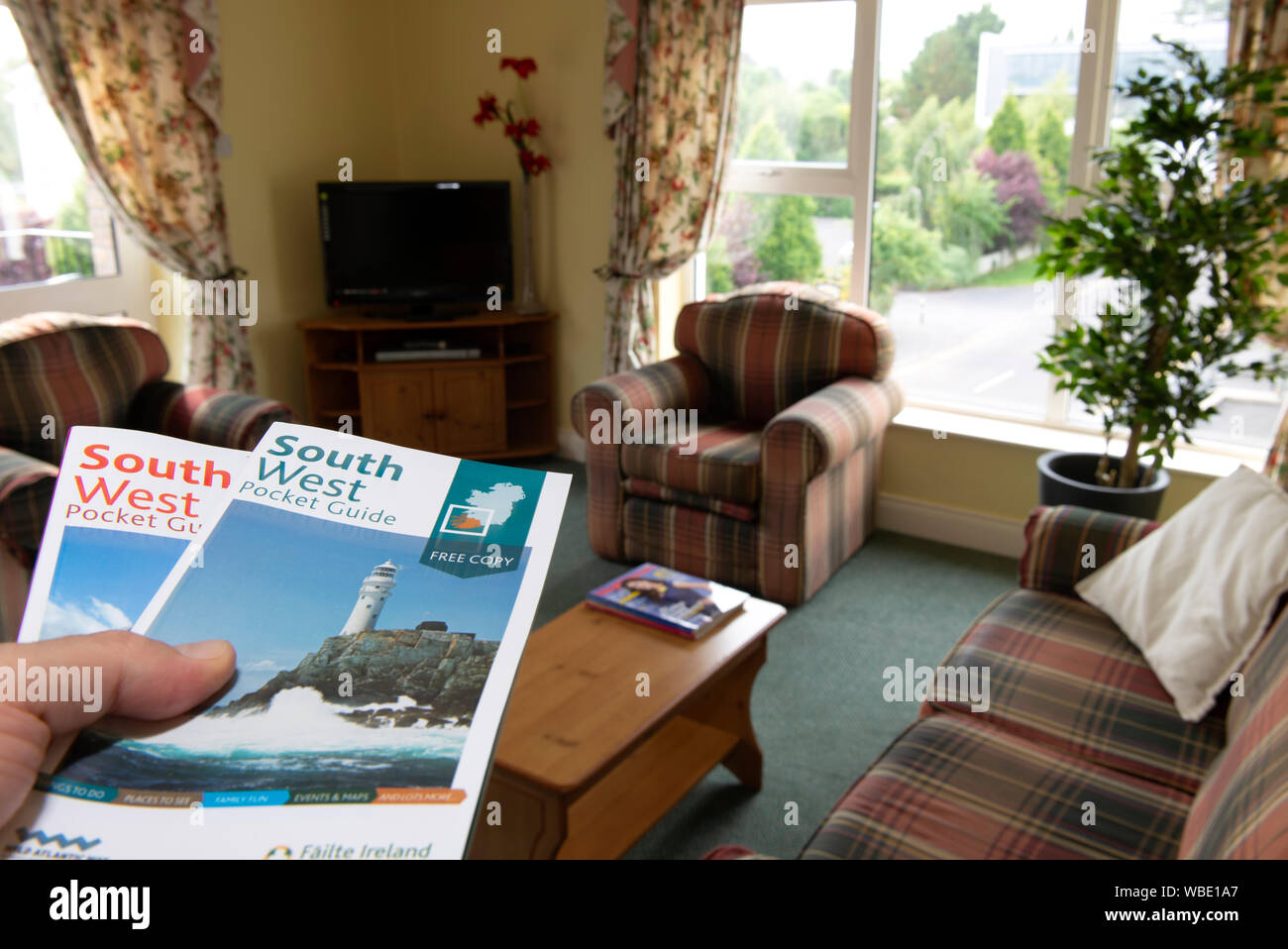 Hand holding pocket travel guide brochures of Southwest of Ireland in a ...