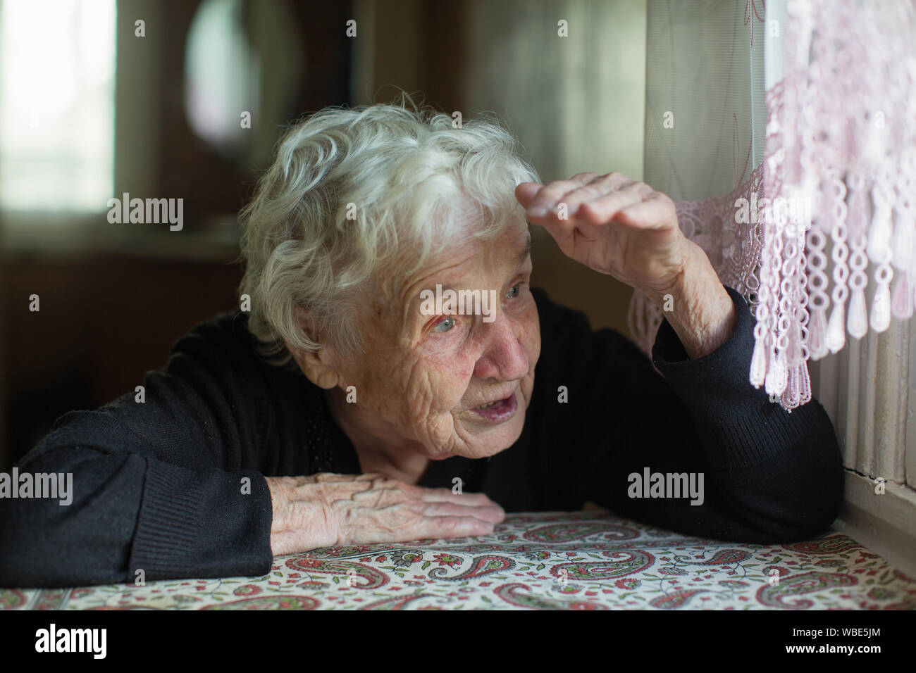 Old lady looks out the window of her house Stock Photo - Alamy