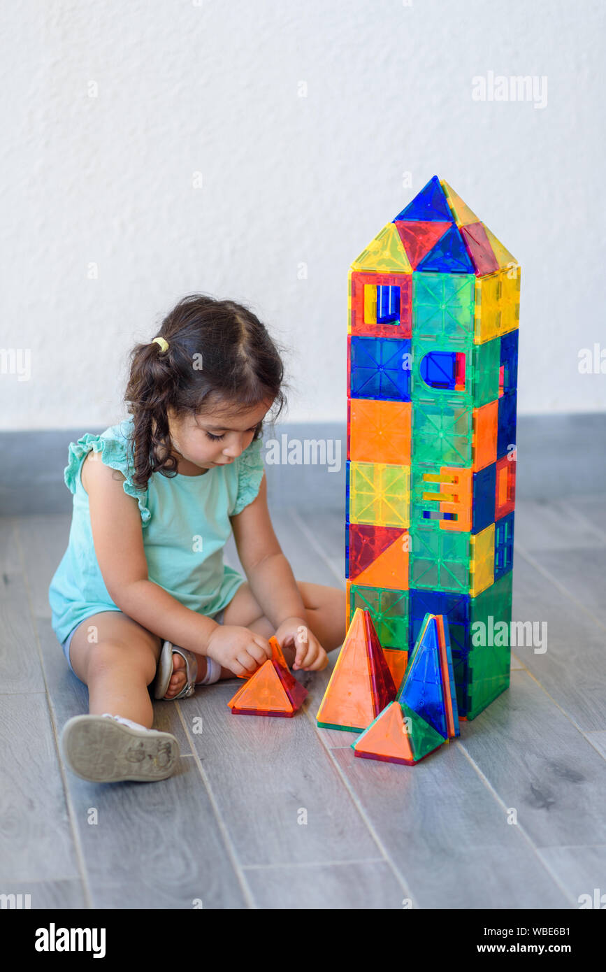 Little girl playing with lots of colorful plastic blocks constructor ...