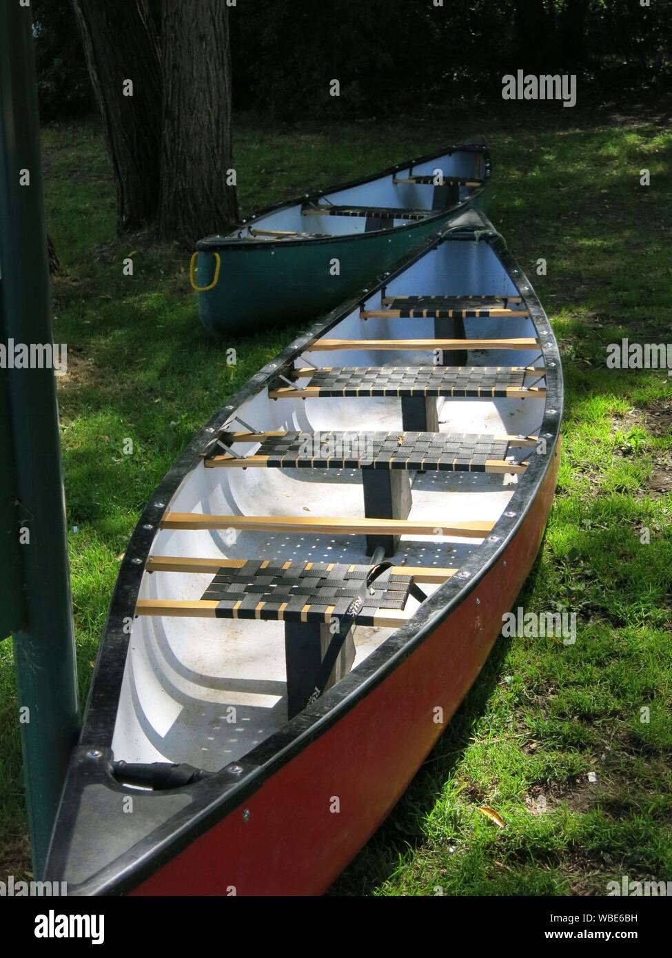 Two colourful rowing boats are sitting on the grassy bank under the ...
