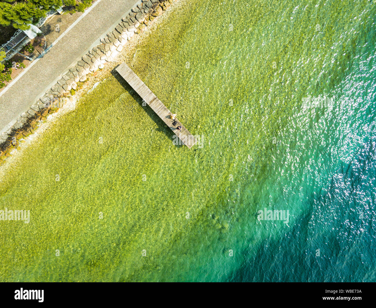 This is an aerial photograph of a wood dock going out into turquoise ...