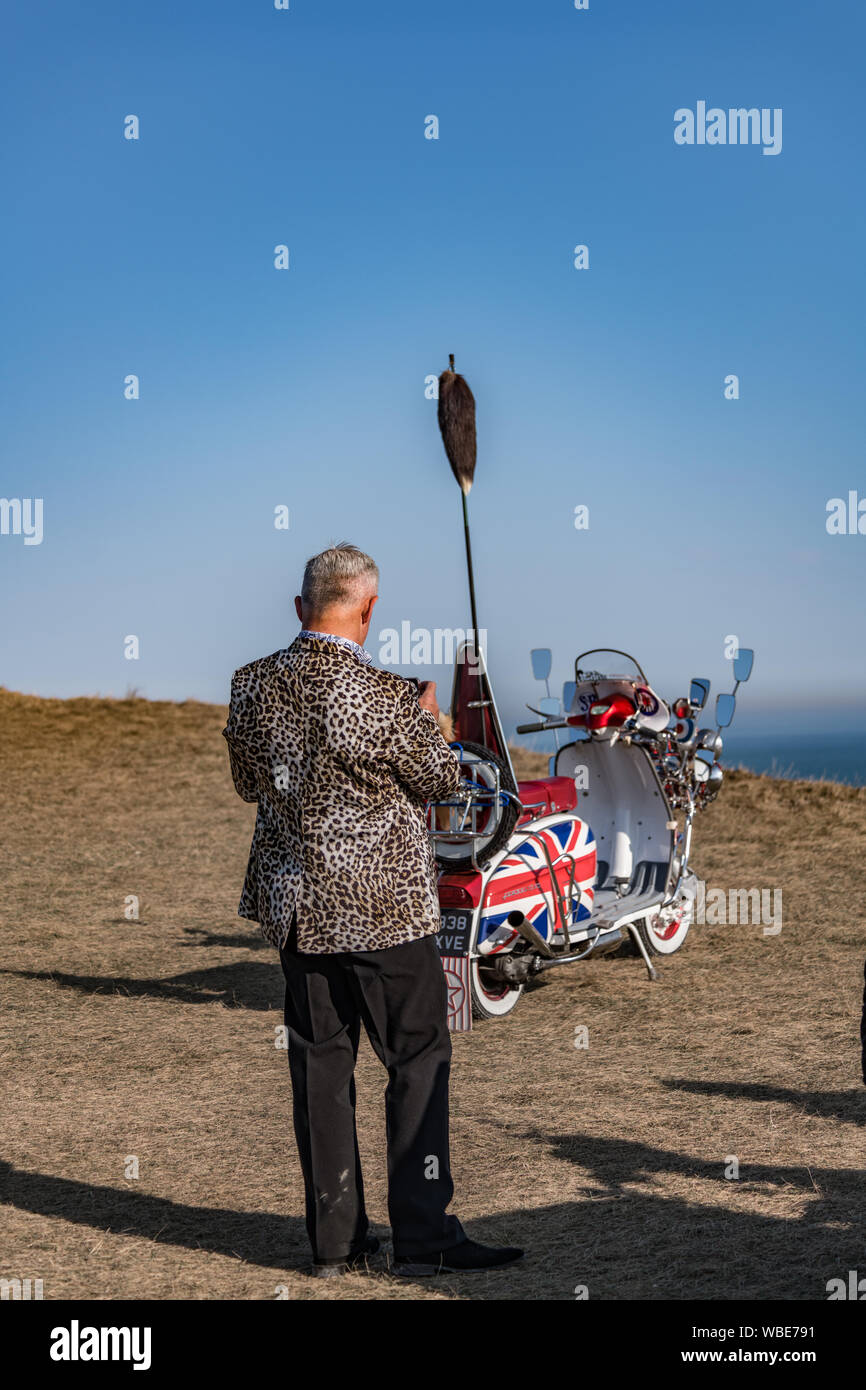 A Mod couple in 1960s attire ride on a Lambretta scooter at Beachy Head ...