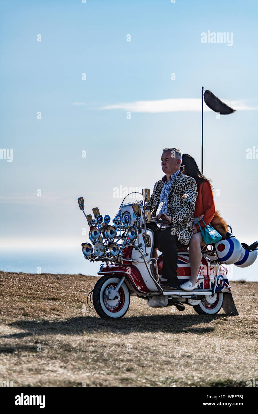 A Mod couple in 1960s attire ride on a Lambretta scooter at Beachy Head ...
