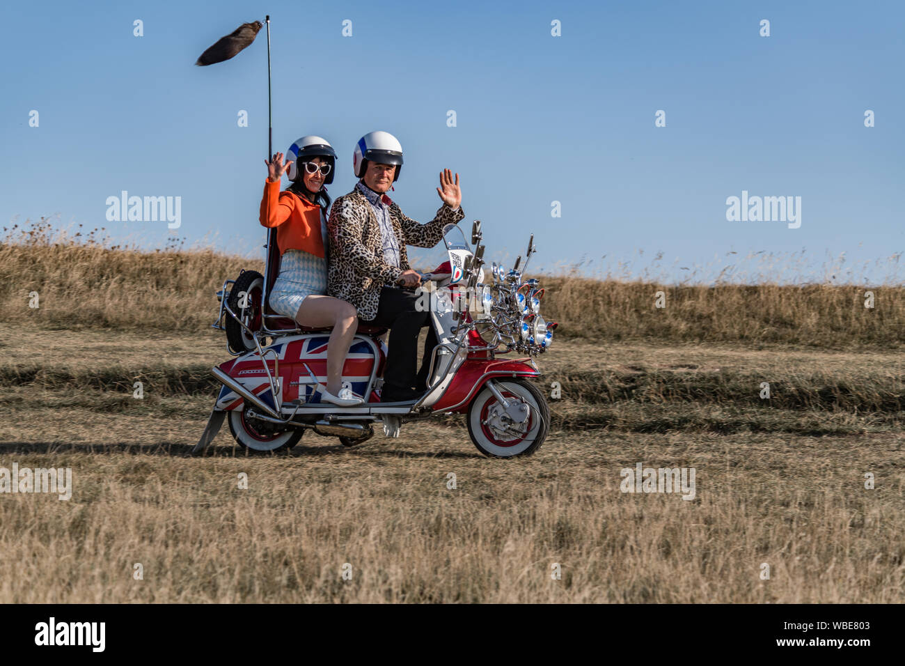A Mod couple in 1960s attire ride on a Lambretta scooter at Beachy Head ...