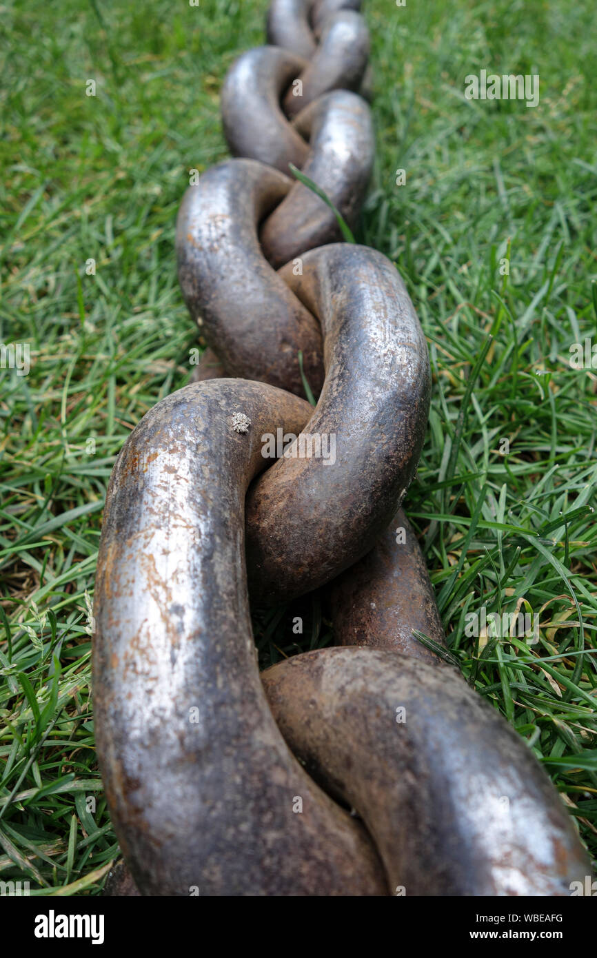 Old log chain isolated on green grass Stock Photo - Alamy