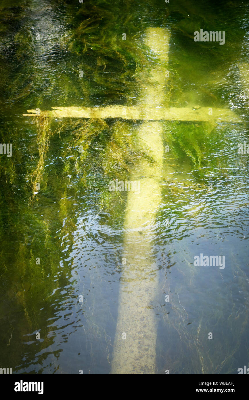 Rustic wooden cross submerged in lake water with reflected clouds Stock ...