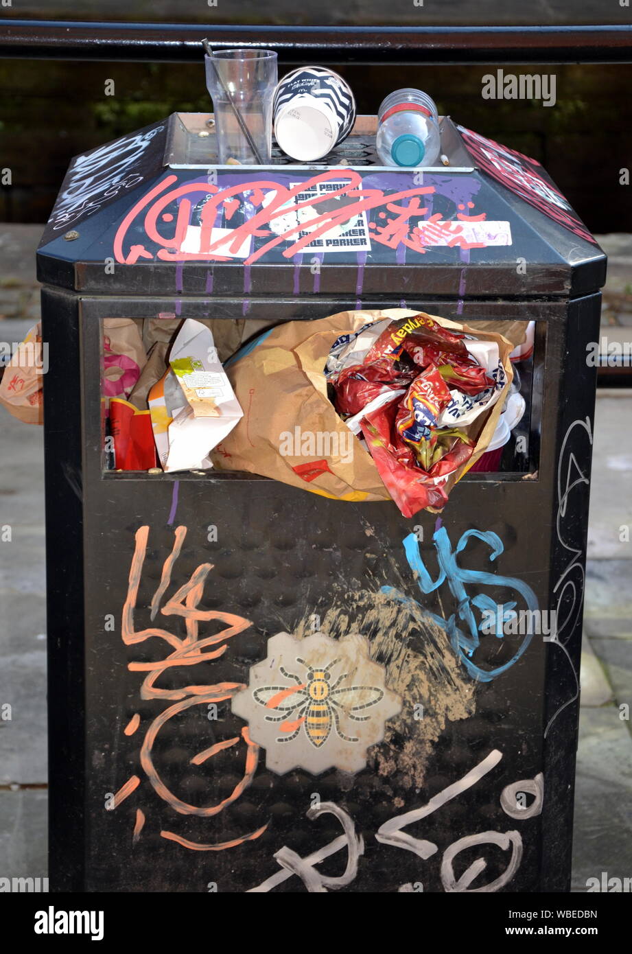 An overflowing rubbish bin with graffiti on in central Manchester, uk ...