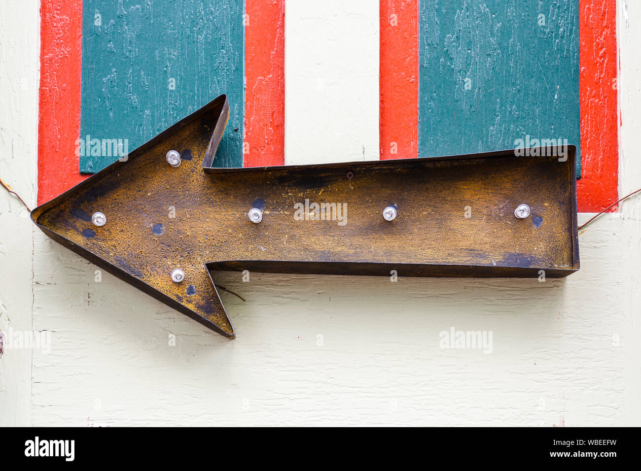 Old rusty arrow sign hung under a patriotic painted wall Stock Photo ...