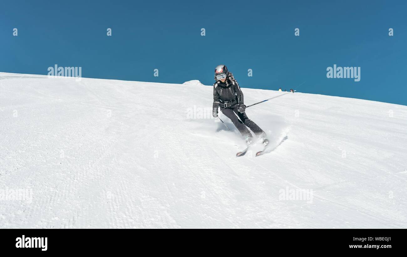 Wide shot of a skier skiing on a snowy surface wearing skiing outfit ...