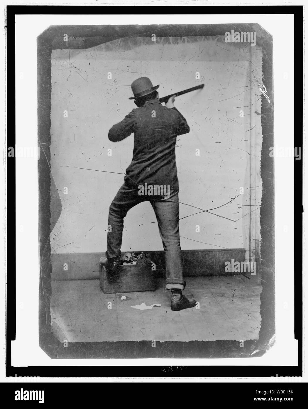 Full-length rear view of a man posed as if shooting a rifle Abstract ...