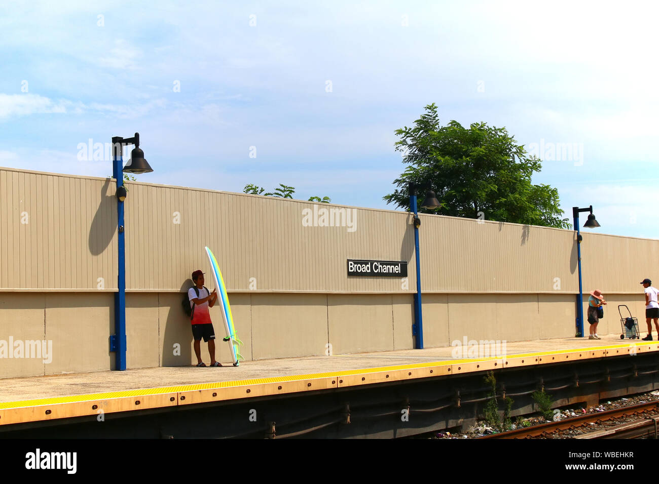 Lone surfer with a surfboard awaits subway train on the Broad Channel ...