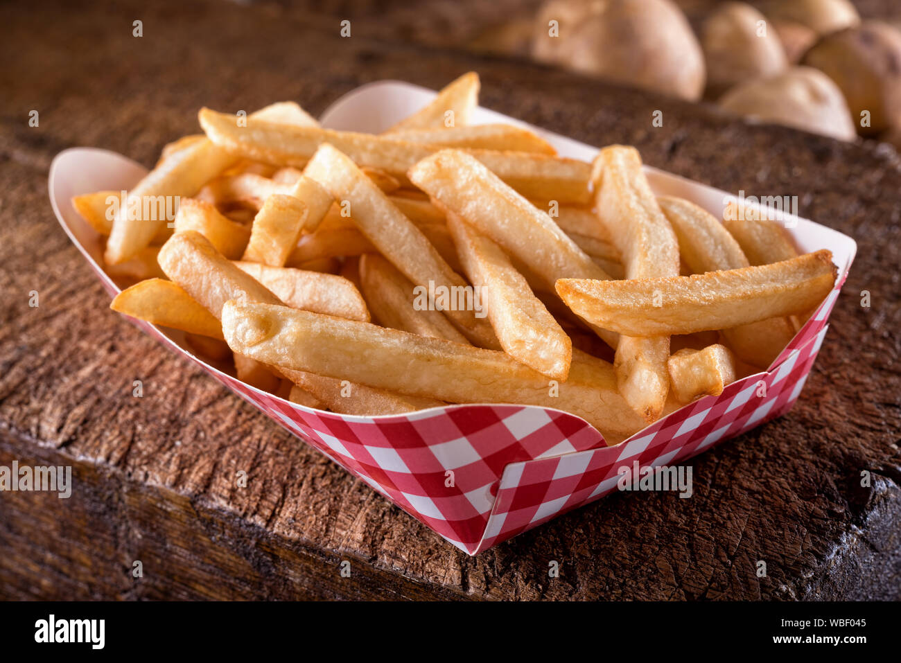 A serving of delicious french fries in take out container on a rustic ...
