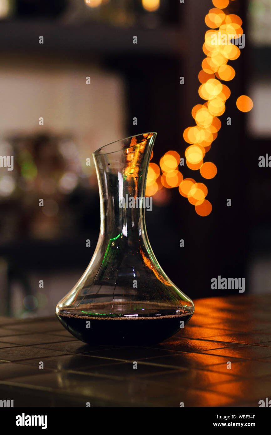 Decanter with red wine stands on bar of restaurant. Colorful bokeh ...