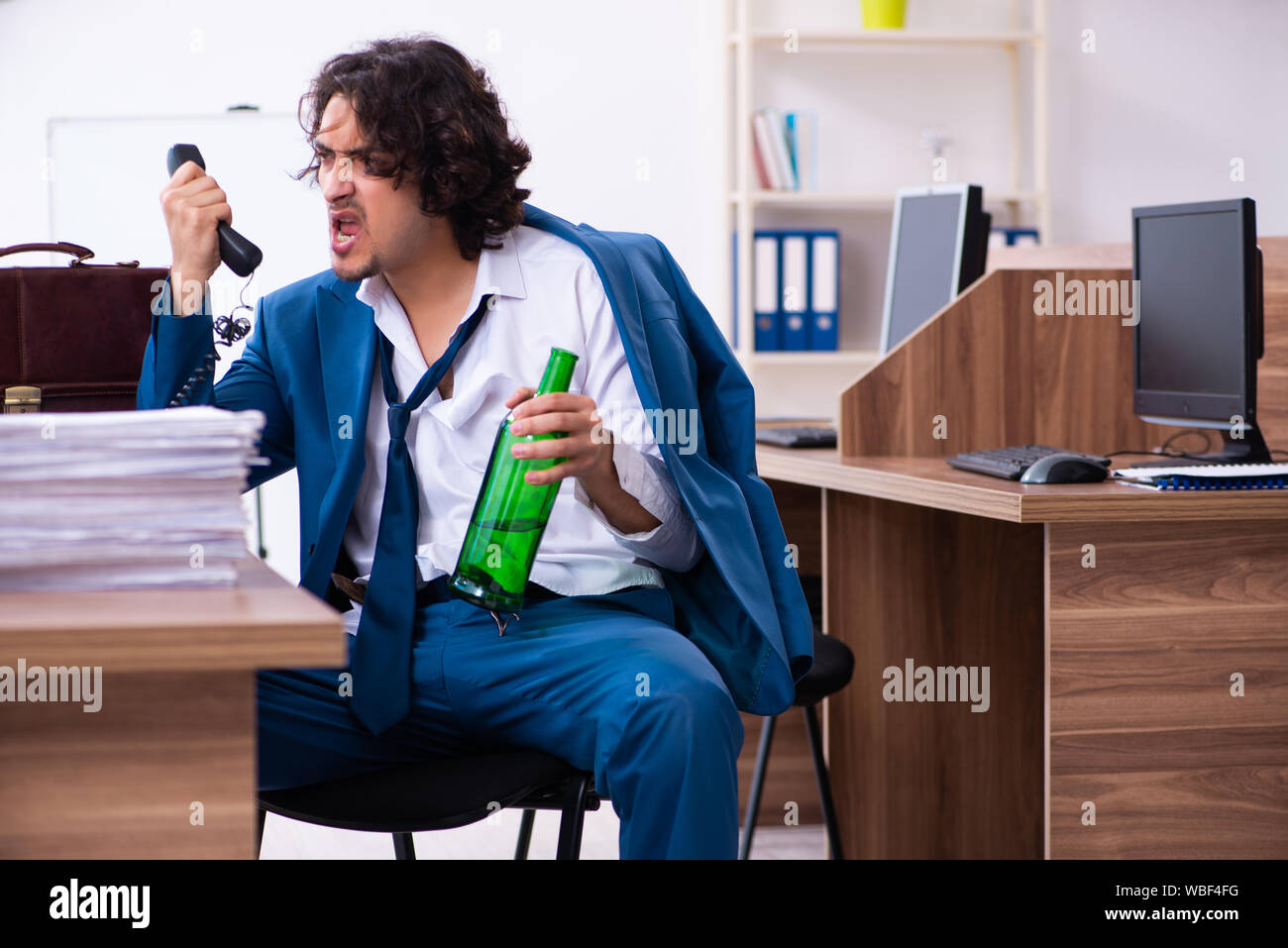 The young drunk employee in the office Stock Photo - Alamy