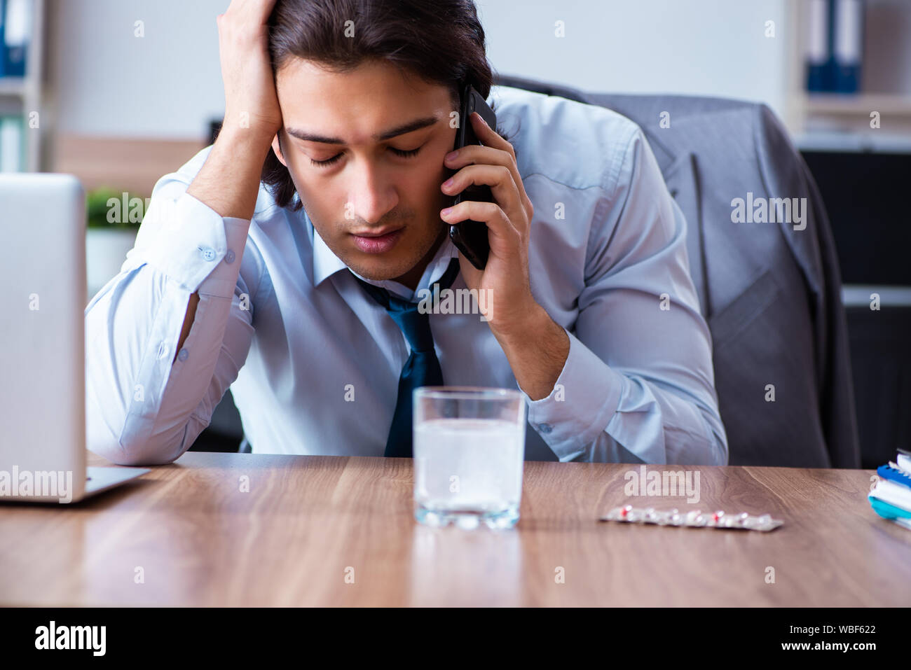 The sick male employee suffering in the office Stock Photo - Alamy