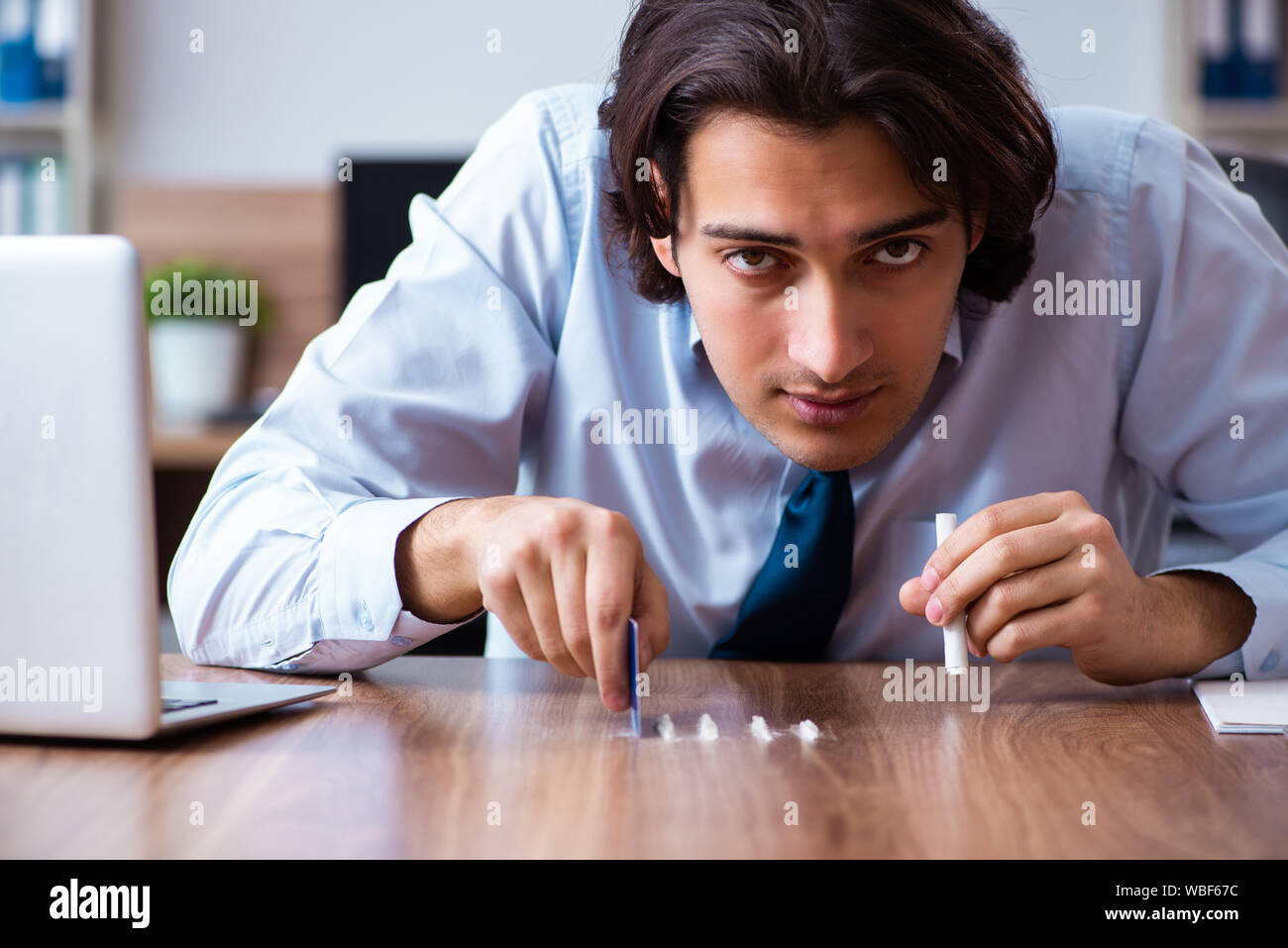 The young man having problems with narcotics at workplace Stock Photo ...