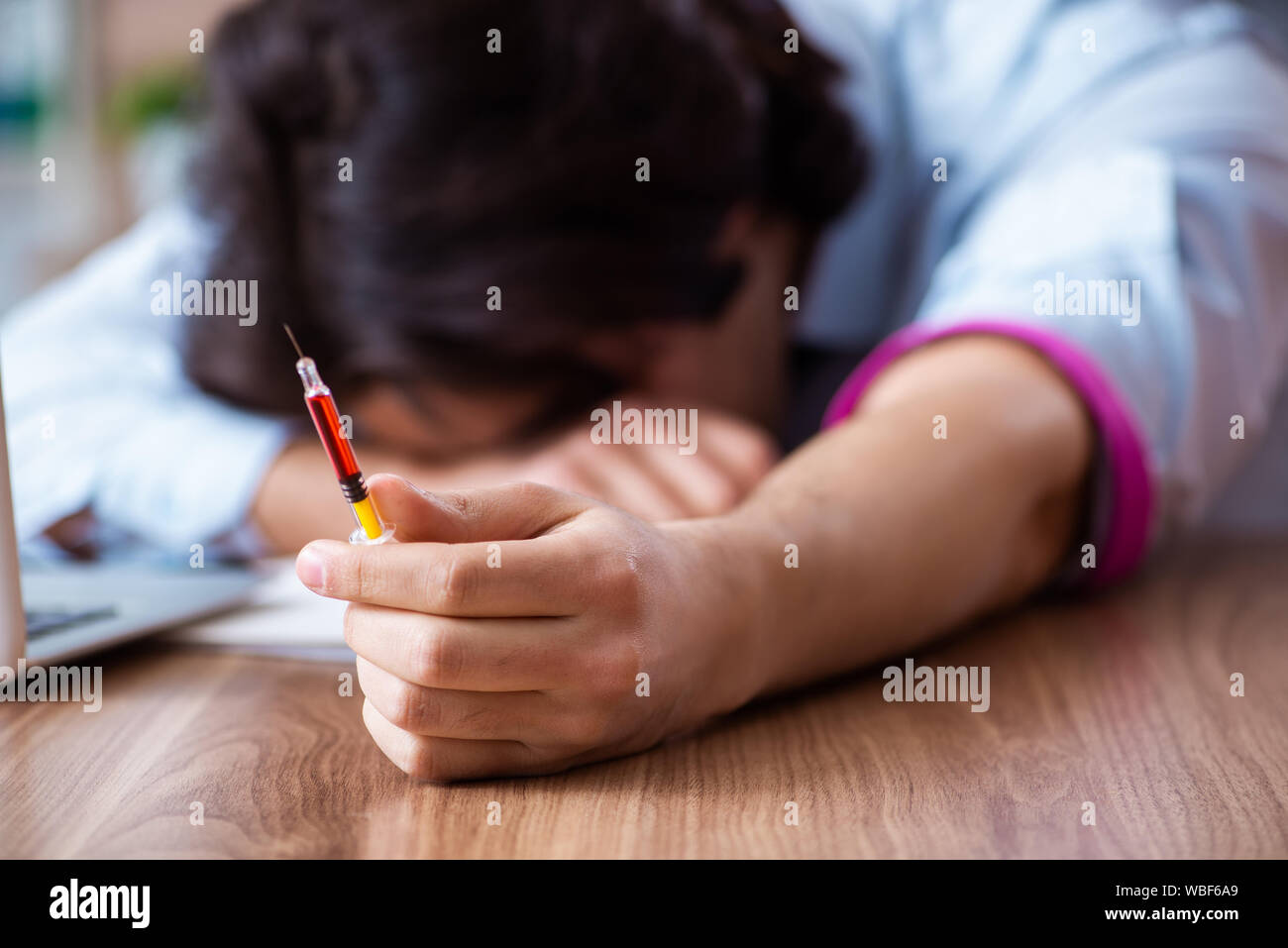The young man having problems with narcotics at workplace Stock Photo ...