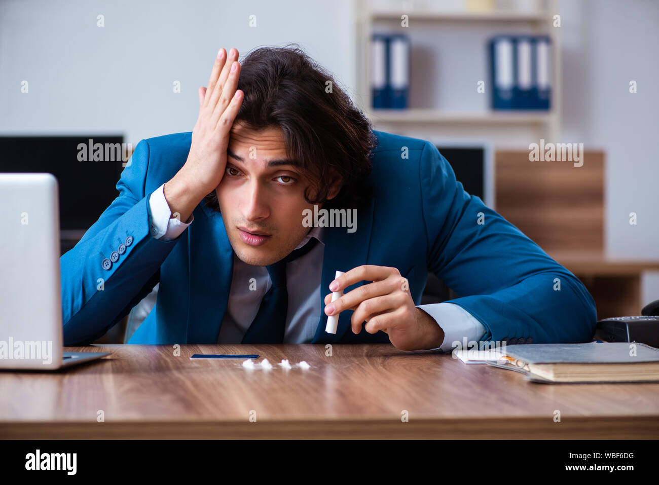 The young man having problems with narcotics at workplace Stock Photo ...