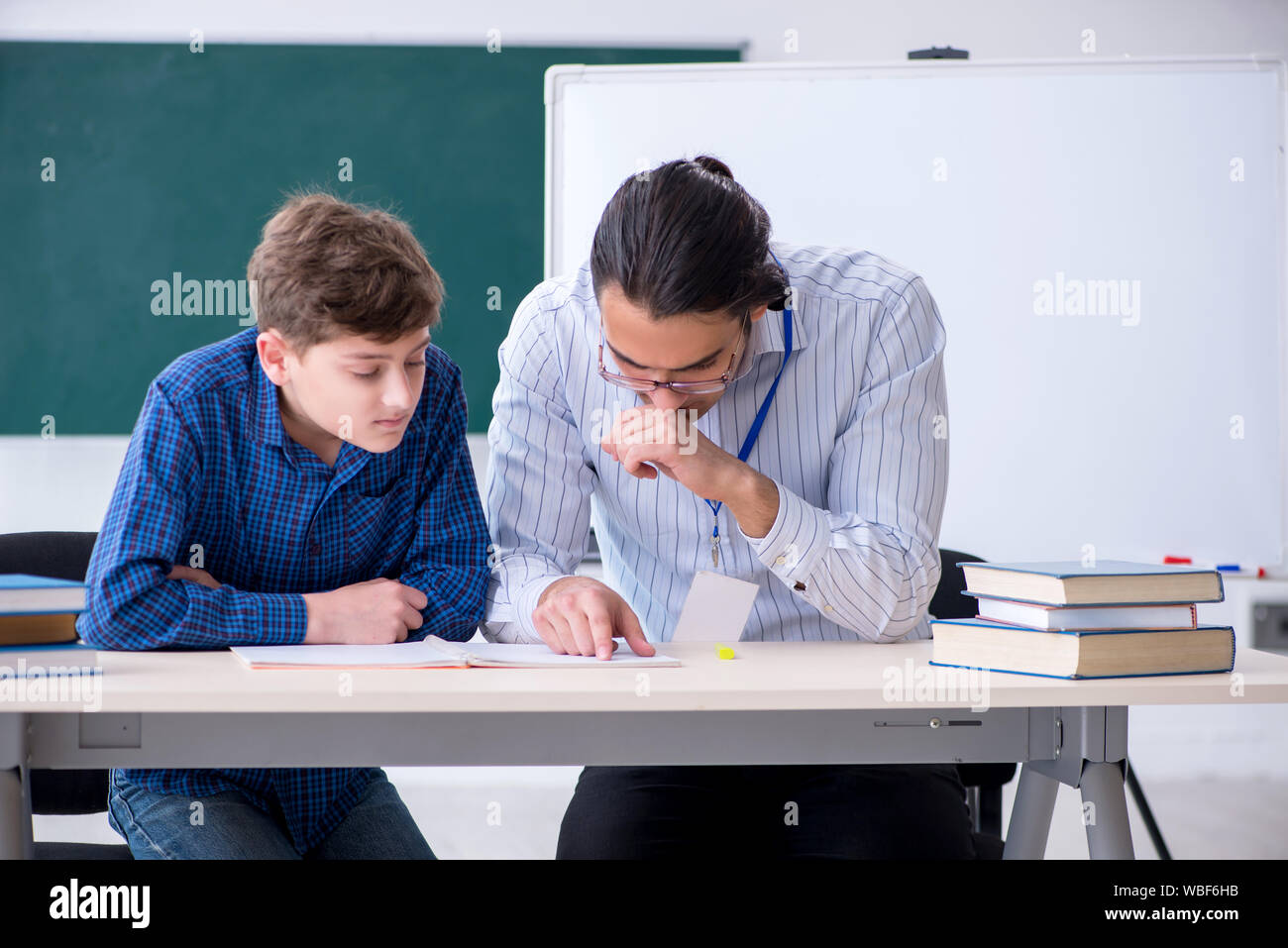 The young male teacher and boy in the classroom Stock Photo - Alamy