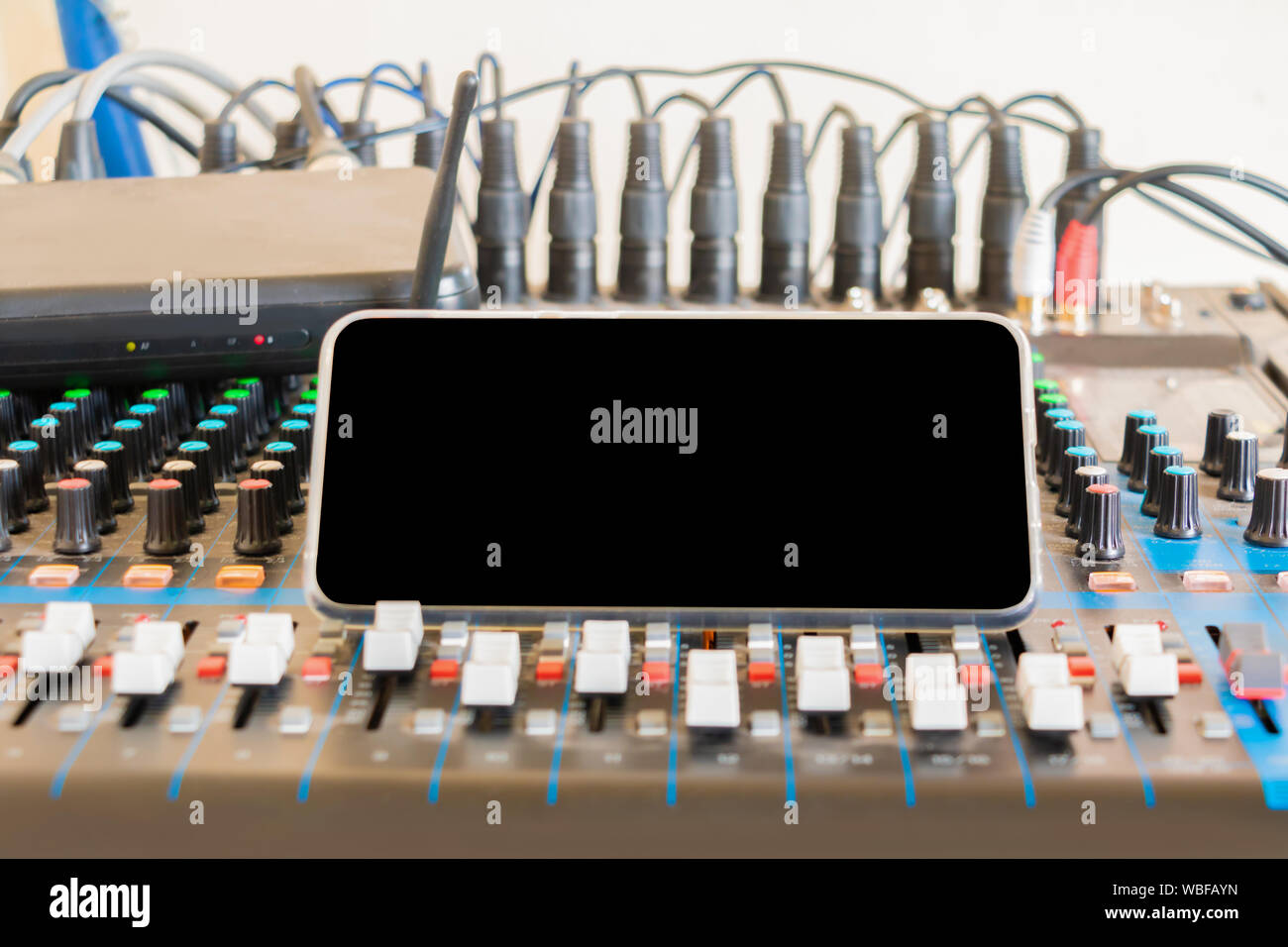 Close up mobile telephone on audio mixer controller in control room ...