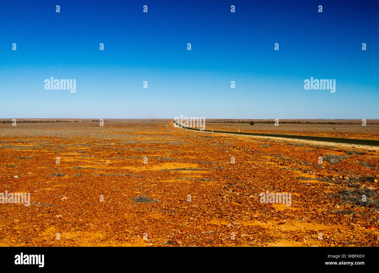 Road stretching across vast red stony barren plains that stretch to ...