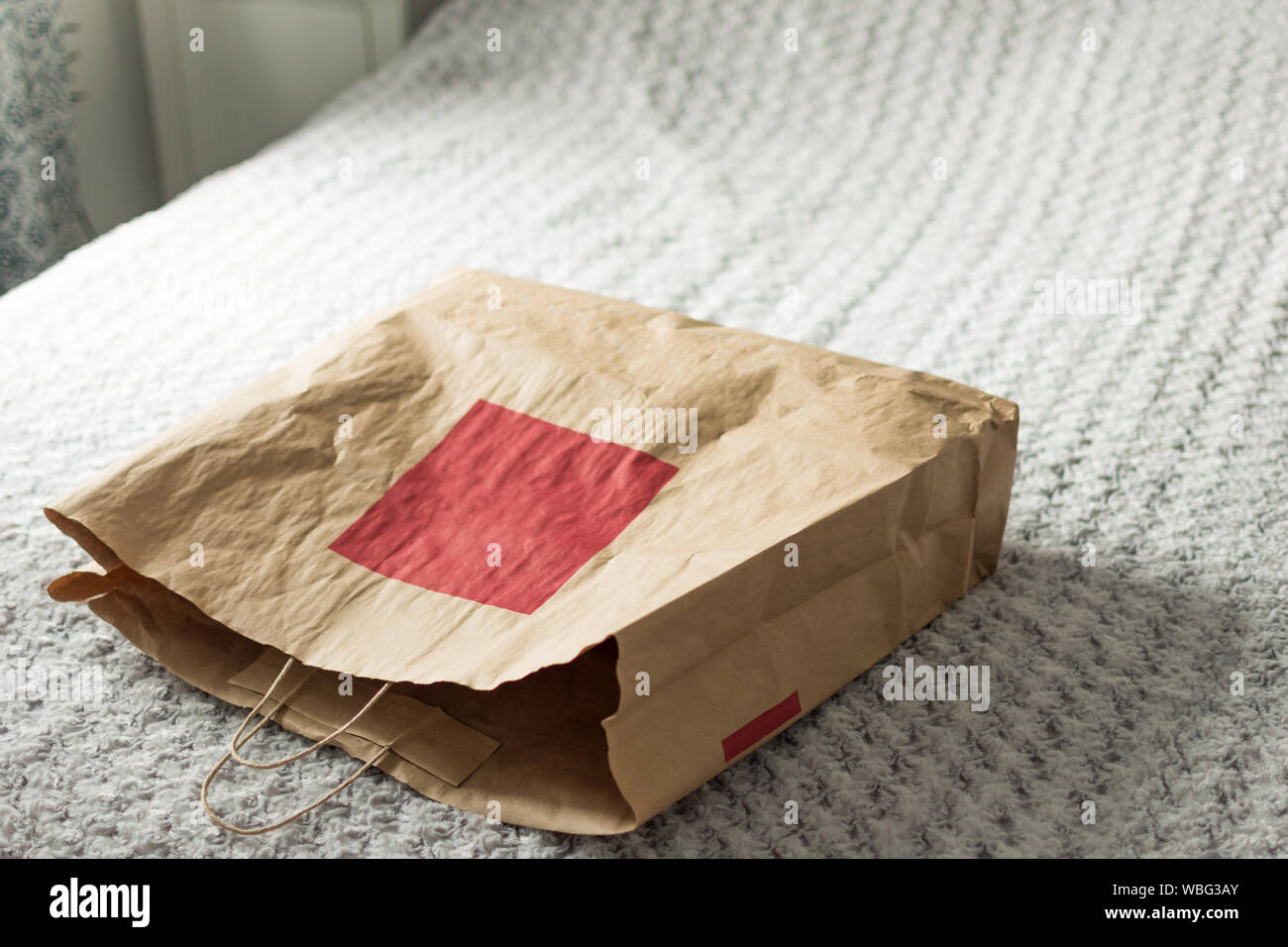Blank paper gift or shopping bag on the bed. Empty paper package for ...