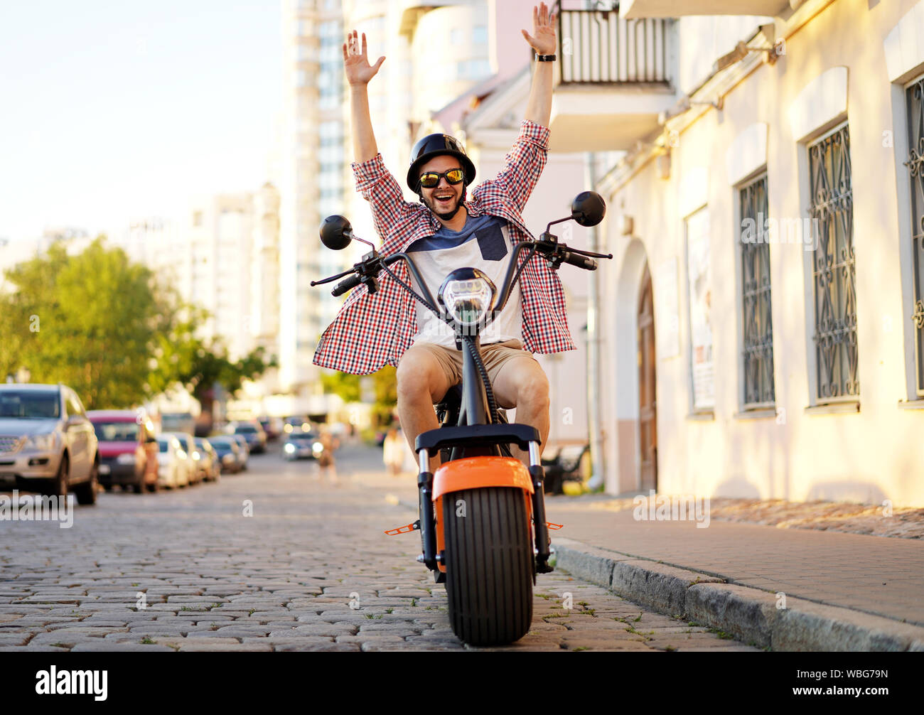 fashionable young man riding a orange motorbike in the street Stock ...