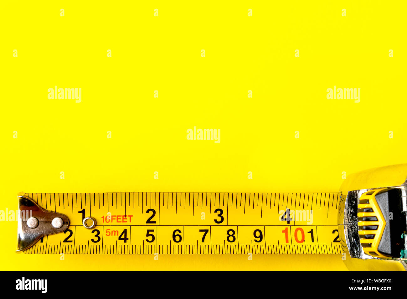 Yellow measuring tape on yellow background Stock Photo - Alamy