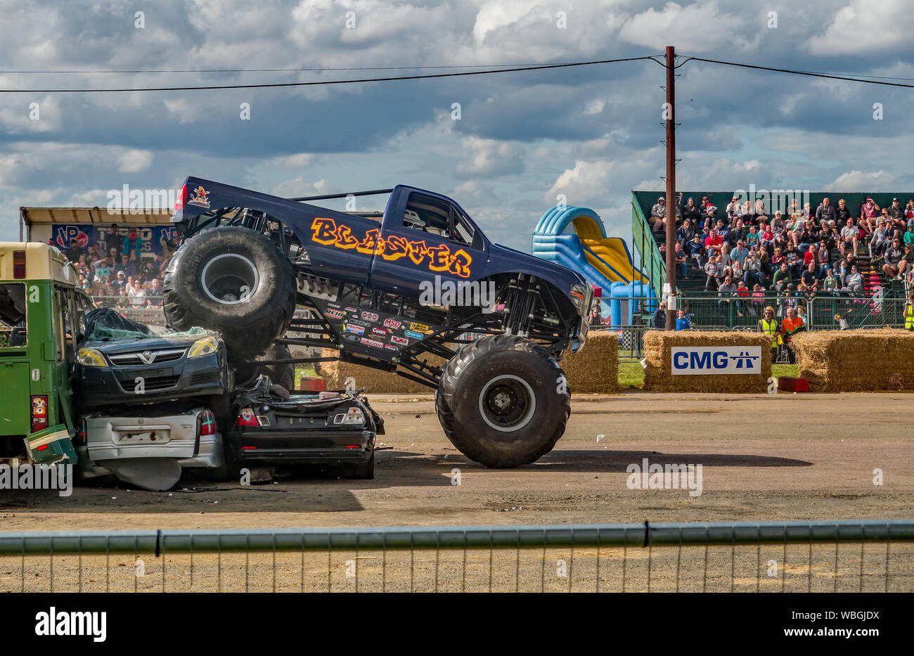The Blaster monster truck landing after jumping a stack of scrap cars ...