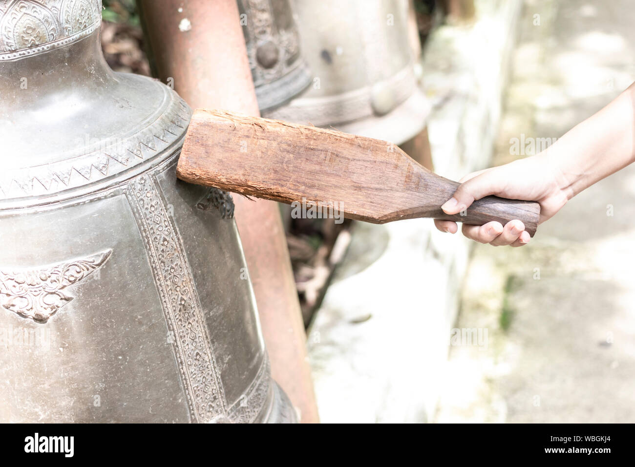 Woman hand holding wood hammer for chime antiques bell in temple. Ring ...