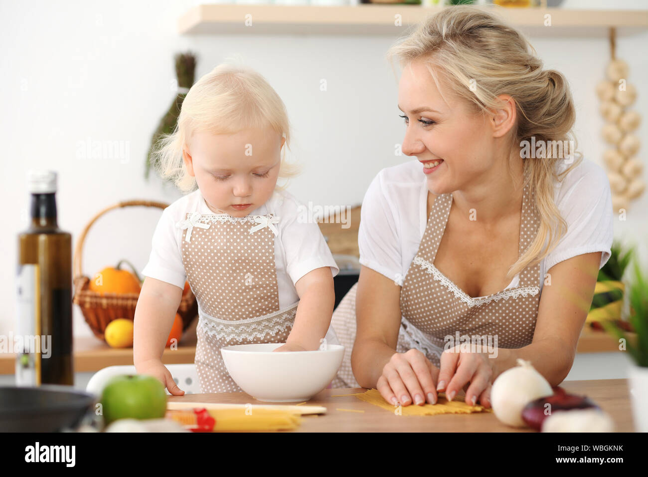Happy mother and little daughter cooking in kitchen. Spending time all ...