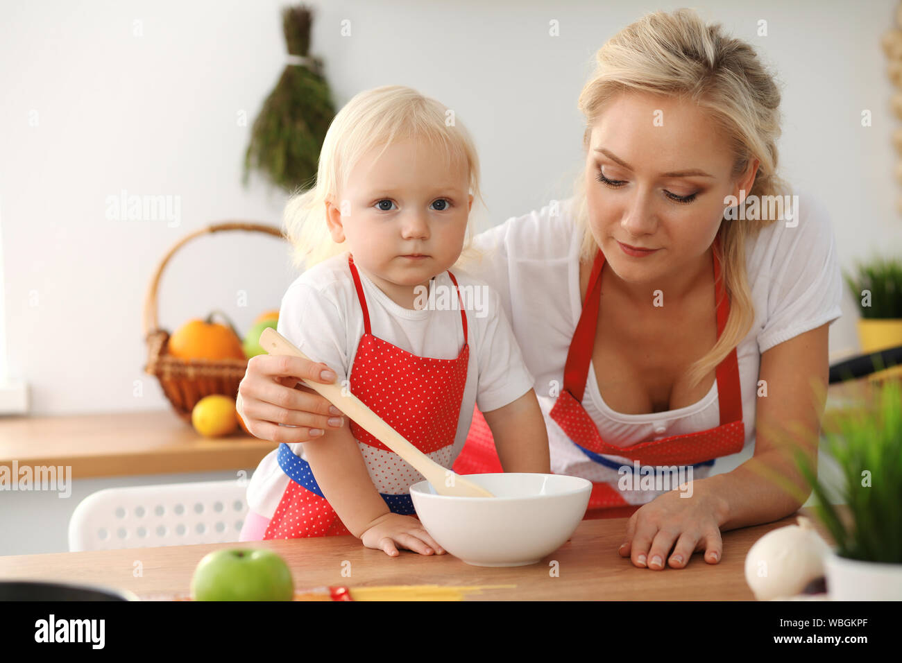 Happy mother and little daughter cooking in kitchen. Spending time all ...