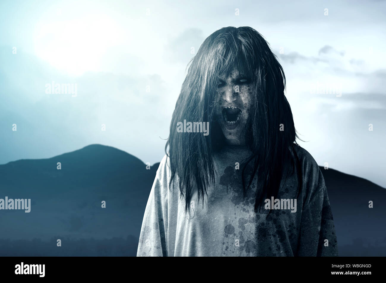 Scary ghost woman with blood and angry face standing on the grassy ...